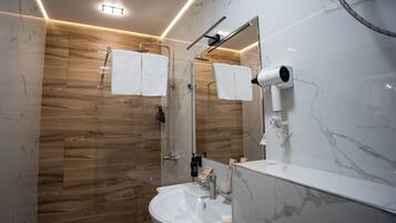 Uma casa de banho moderna com cabine de duche em madeira, lavatório branco e espelho grande.