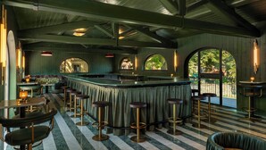 Uma área de bar com teto alto, vigas de madeira e balcão com banquetas.