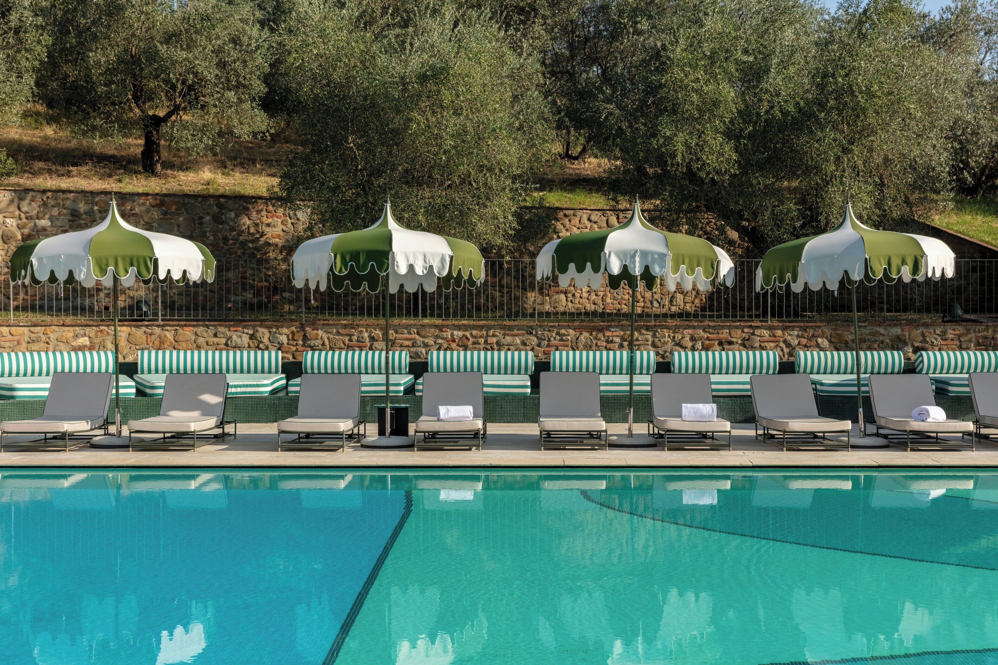 Área de piscina com espreguiçadeiras e guarda-sóis.