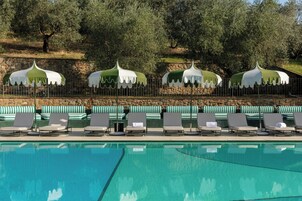 Área de piscina com espreguiçadeiras e guarda-sóis.