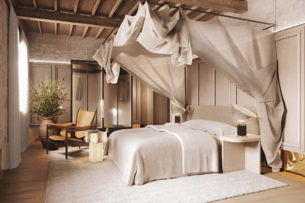 Quarto com cama de dossel, mesa de cabeceira, cadeira, planta em vaso e um espelho grande.
