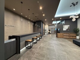 Uma área de recepção moderna com parede de tijolos, um balcão de atendimento e uma fileira de bancos de madeira.