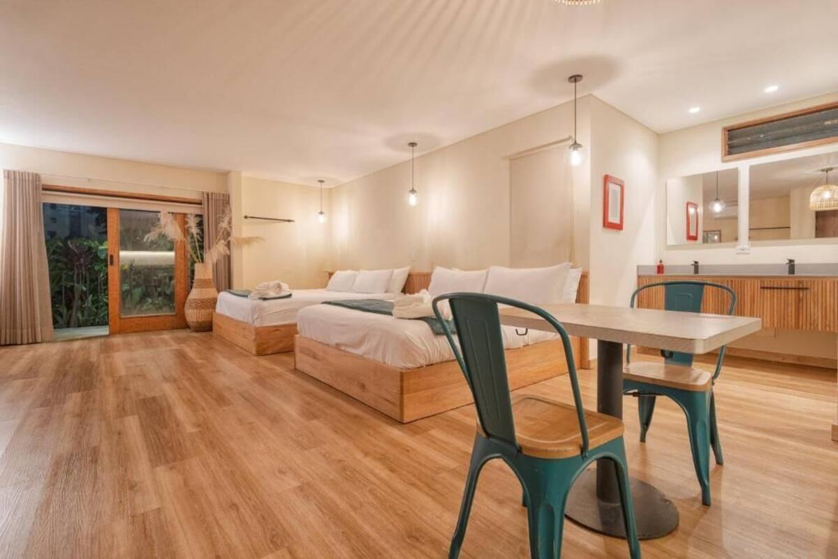 Quarto moderno com cama de madeira, mesa de jantar com cadeiras e uma janela grande com cortinas.