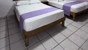 Quarto de hotel com duas camas, piso de azulejos e iluminação no teto.