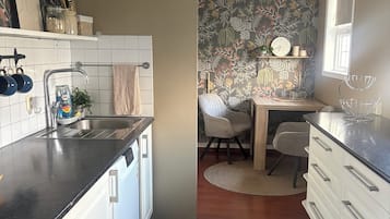 Cozinha compacta com armários brancos, bancada preta e painel de azulejos.
