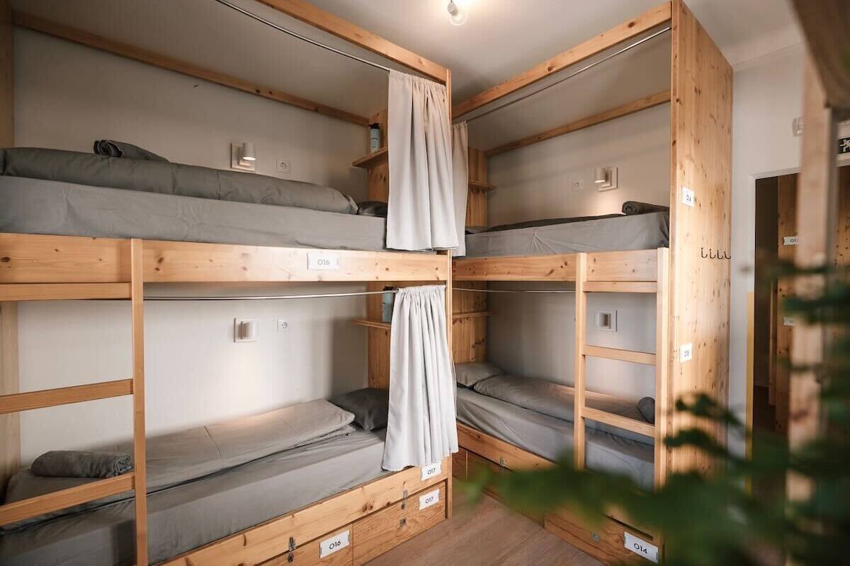 Um quarto tipo dormitório com beliches, paredes de madeira e design simples e funcional.
