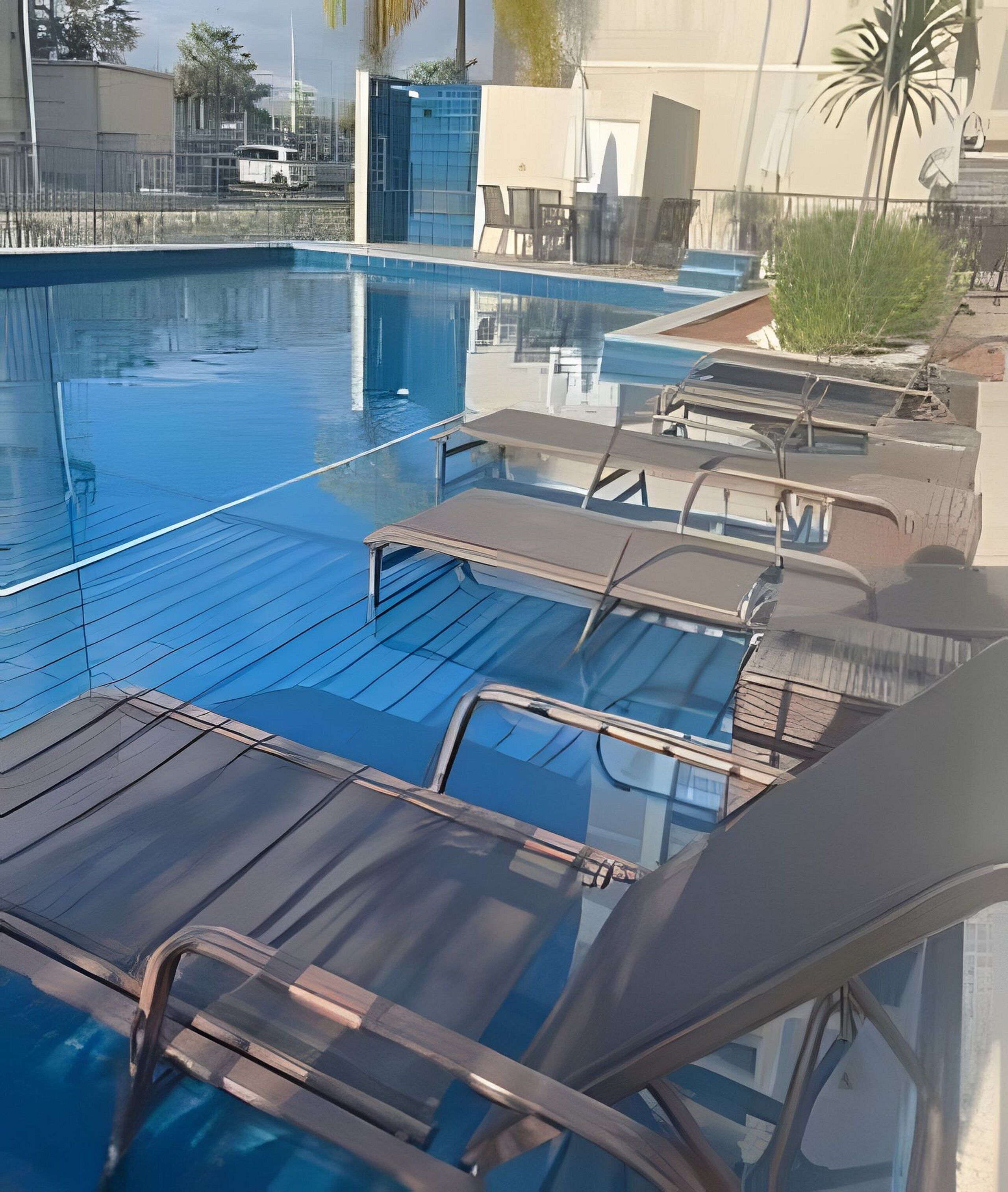 Uma piscina com espreguiçadeiras e barreira de vidro.