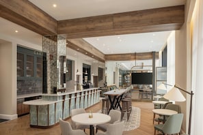 Uma cozinha moderna com área de bar, vigas de madeira e um espaço de refeições com mesas e cadeiras redondas.