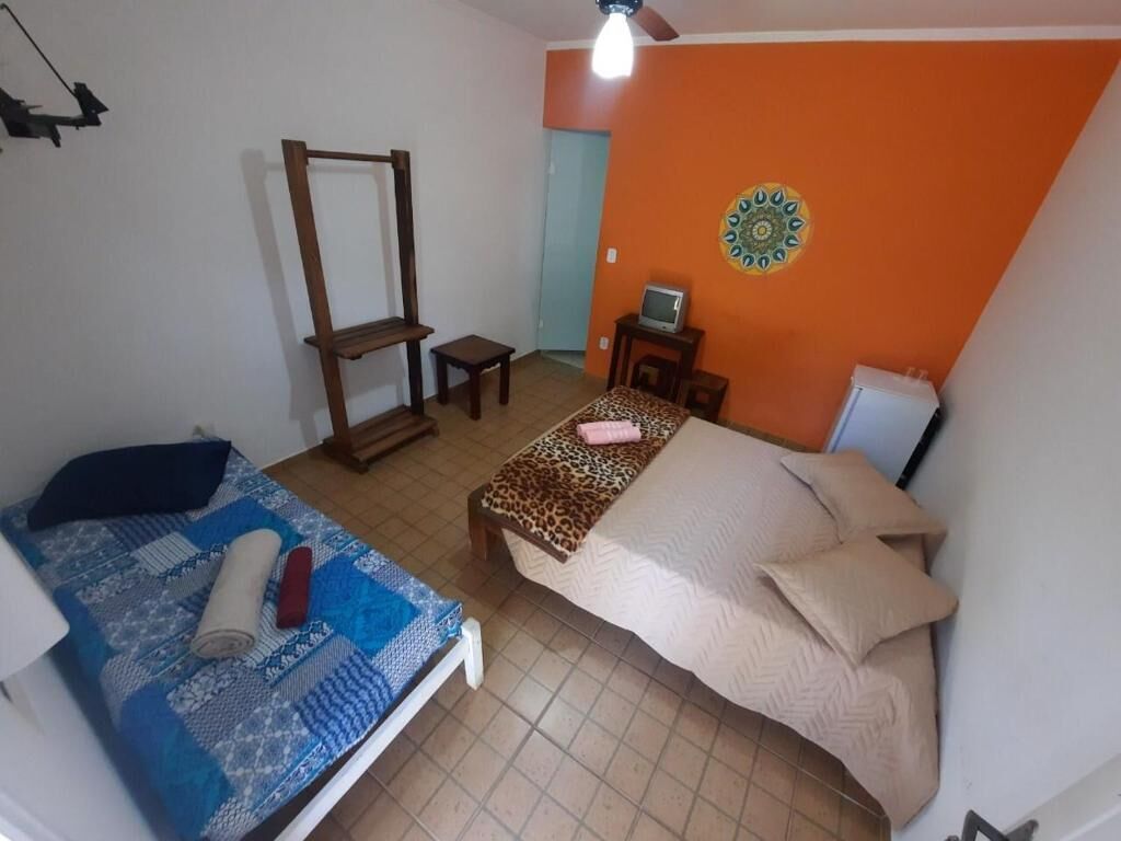 Quarto com cama, cadeira, escrivaninha e espelho.