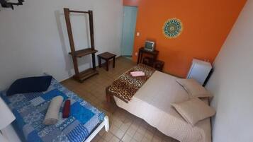 Quarto com cama, cadeira, escrivaninha e espelho.