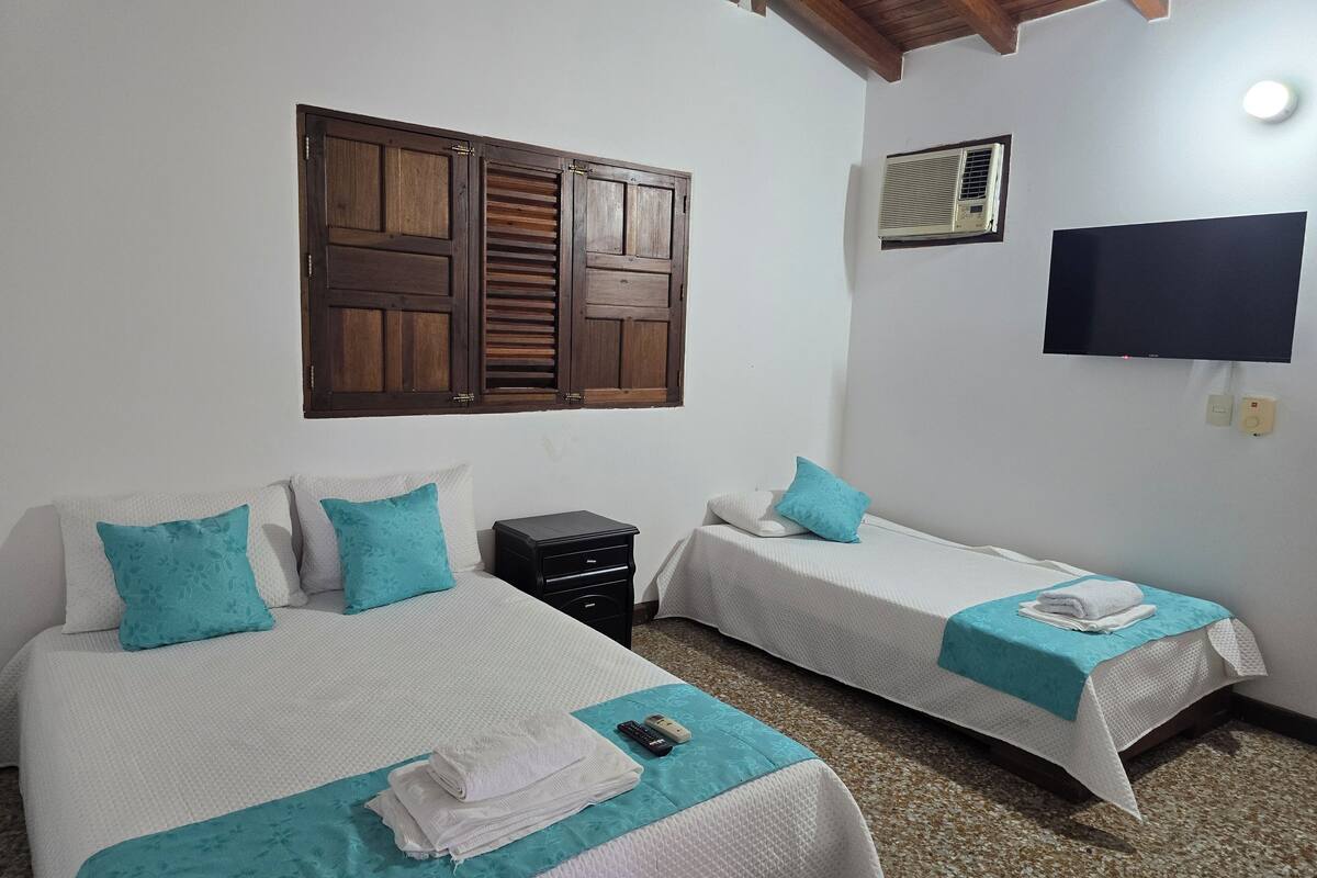 Quarto com duas camas, televisão, aquecedor e uma pequena mesa.