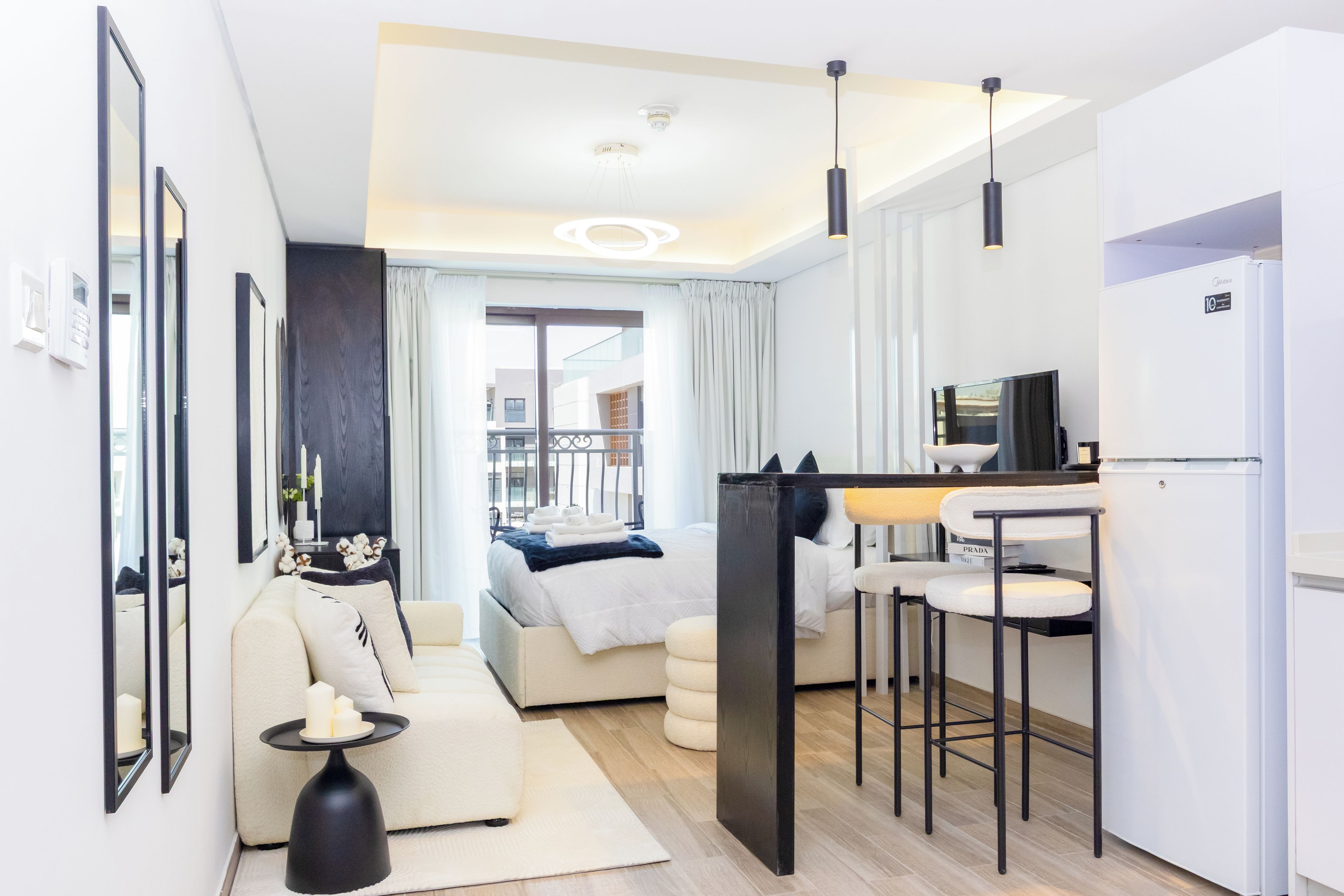 Quarto de hotel moderno com sofá, área de jantar, cozinha e varanda com vista.