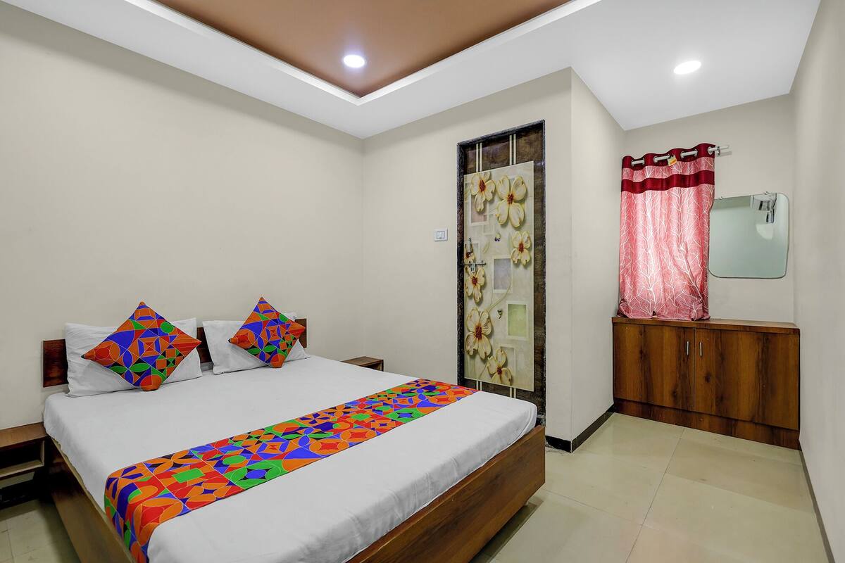 Quarto com cama, mesa de cabeceira de madeira, guarda-roupa e porta com desenho floral.