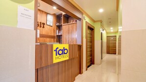 Uma área de recepção de hotel com um balcão de madeira e uma placa com 'Fab Hotels'.