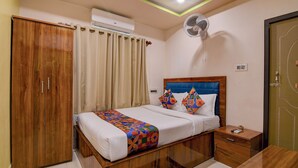 Quarto com cama de madeira, mesa de cabeceira, guarda-roupa, ar-condicionado e ventilador de teto.