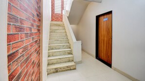 Uma escadaria com degraus brancos que leva a uma porta de madeira com o número 207.