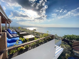 Terraço no telhado com espreguiçadeiras e vista para o mar.