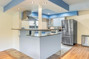 Cozinha moderna com ilha central, eletrodomésticos de aço inoxidável e paredes com detalhes em azul.