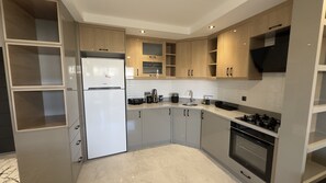 Cozinha moderna com geladeira, fogão e forno embutidos.