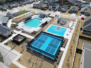 Vista aérea de um bairro residencial com várias casas, piscina e quadra de tênis.