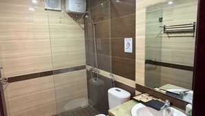 Casa de banho com sanita, lavatório, espelho, chuveiro e sistema de ventilação.