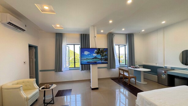 Quarto de hotel com cama, escrivaninha, cadeira, TV e vista para o exterior.