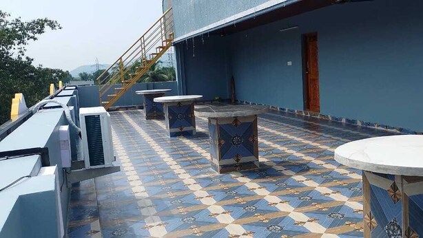 Um terraço no telhado com piso estampado, mobiliário de exterior e aparelhos de ar condicionado.