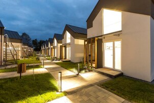 Uma fileira de casas modernas, térreas, com grandes janelas e um gramado bem cuidado.