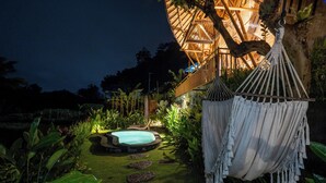 Uma rede, uma banheira de hidromassagem e uma estrutura de madeira com telhado.