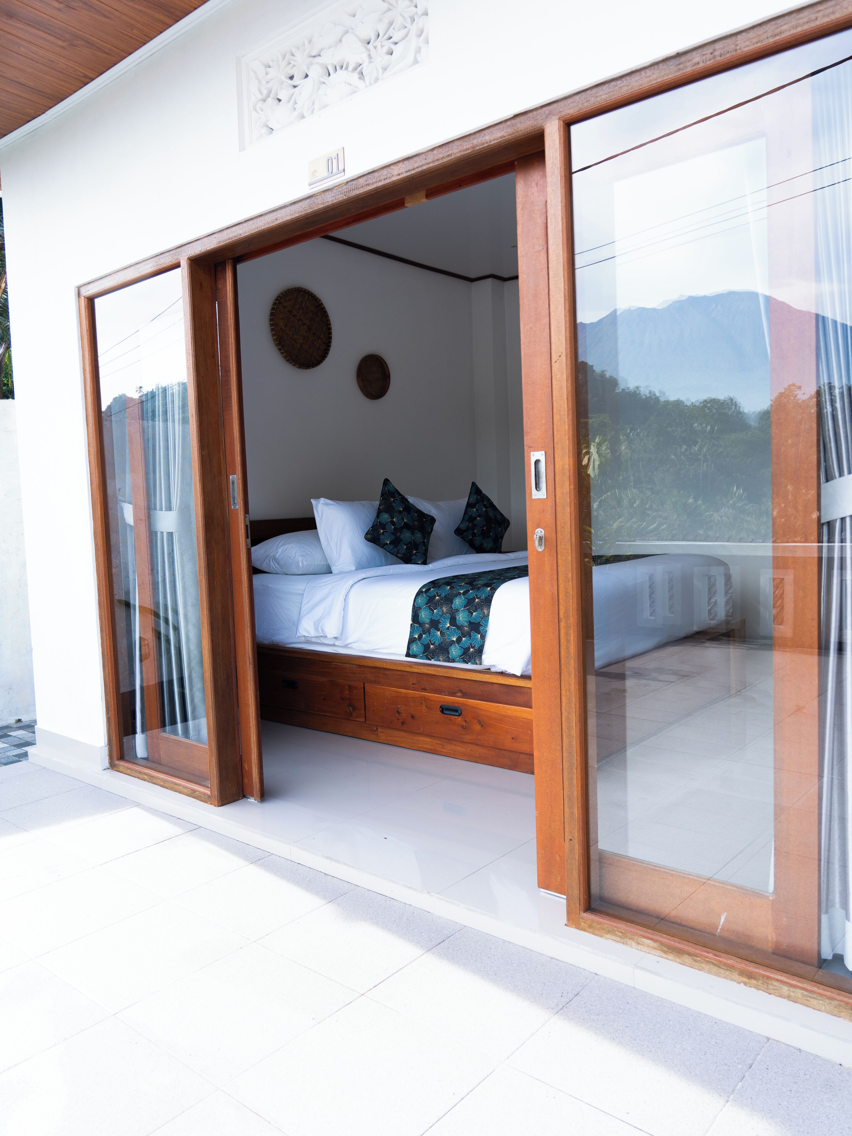 Quarto com cama de madeira, porta de vidro deslizante e vista para o exterior.