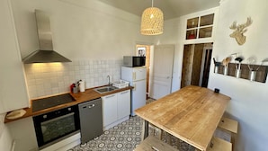 Uma cozinha compacta com azulejos brancos, bancada de madeira, forno embutido e micro-ondas.