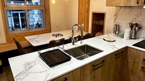Cozinha moderna com armários de madeira, bancada de mármore e pia embutida.
