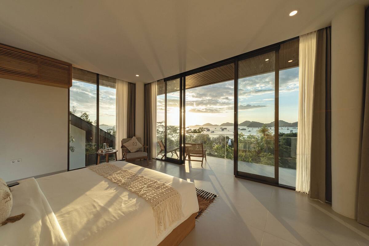 Quarto moderno com uma cama grande, vista para o exterior e uma varanda com área de estar.