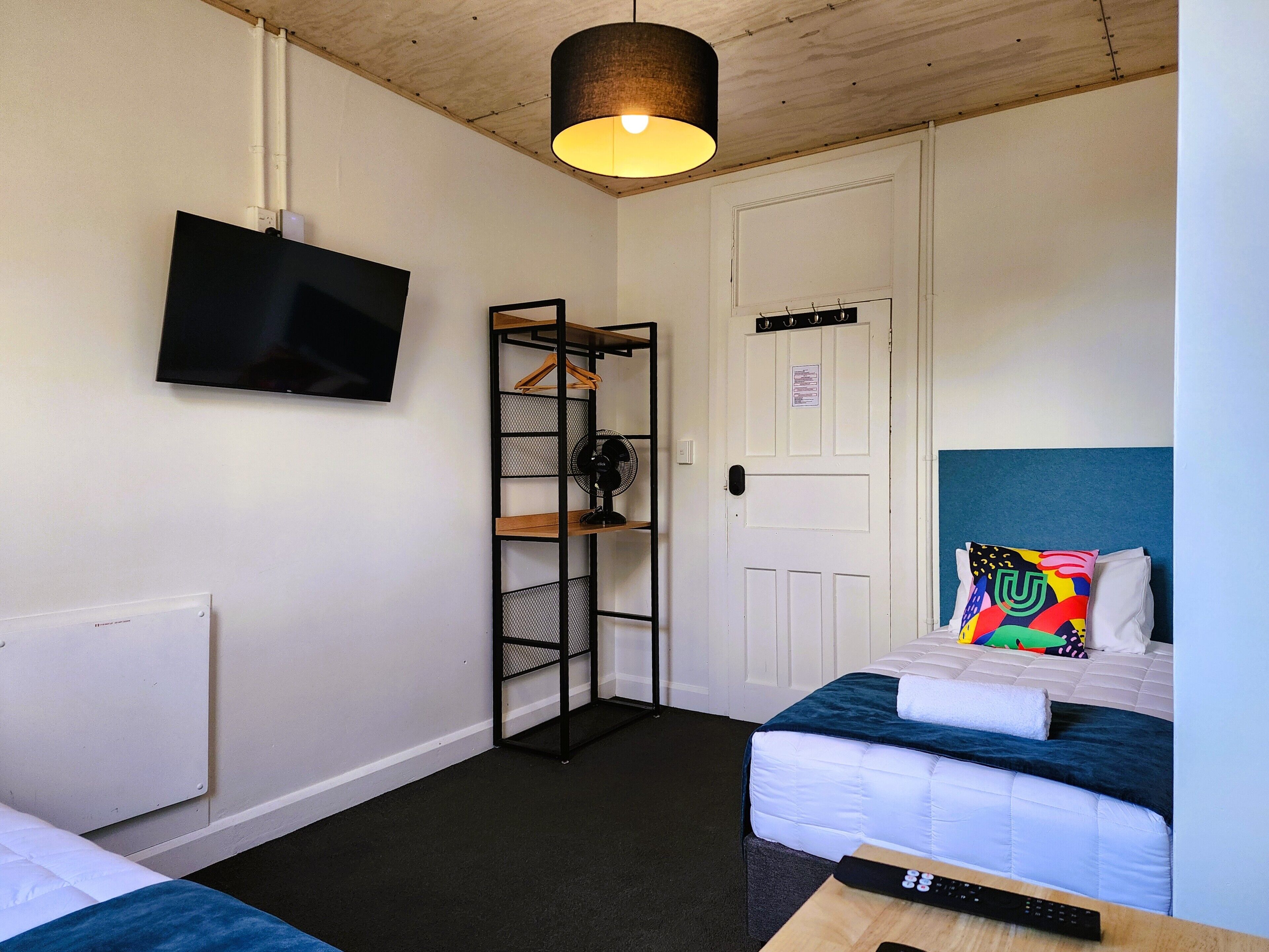 Quarto de hotel com cama, televisão, guarda-roupa e secretária.
