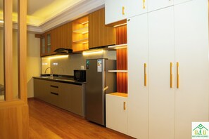 Uma cozinha moderna com armários de madeira, geladeira de aço inoxidável e micro-ondas.