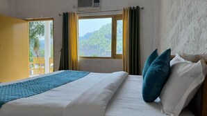 Quarto de hotel com cama, janela com cortinas e vista para o verde lá fora.