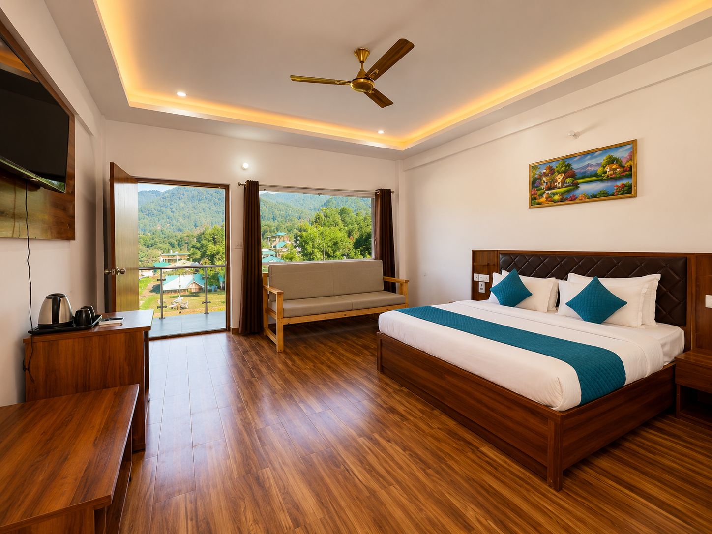 Quarto de hotel com cama, sofá, escrivaninha e ventilador de teto.