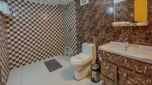 Casa de banho com chão padronizado em xadrez, sanita, lavatório e espelho.