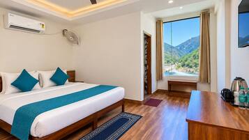 Quarto de hotel com cama, escrivaninha, cafeteira e vista para uma paisagem montanhosa.