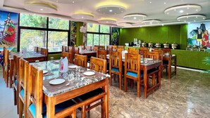 Um restaurante com mesas e cadeiras redondas, uma parede verde e um mural na parede.