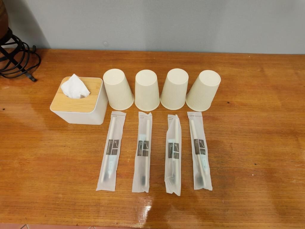 Uma mesa de madeira com cinco copos de papel brancos e uma caixa de lenços.