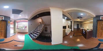 Um saguão de hotel com escadaria, balcão de recepção e área de atendimento.