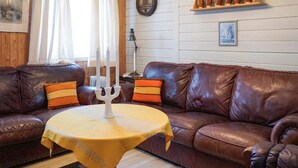Uma sala de estar acolhedora com um sofá de couro marrom, uma mesinha redonda com toalha de mesa amarela e um candelabro.