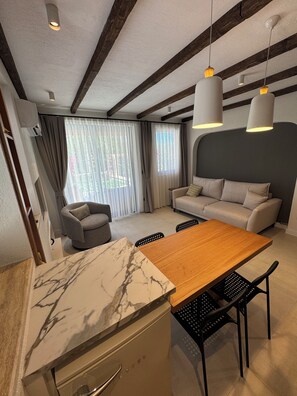 Uma sala de estar moderna com uma ilha de cozinha em mármore, um sofá e uma mesa de jantar.