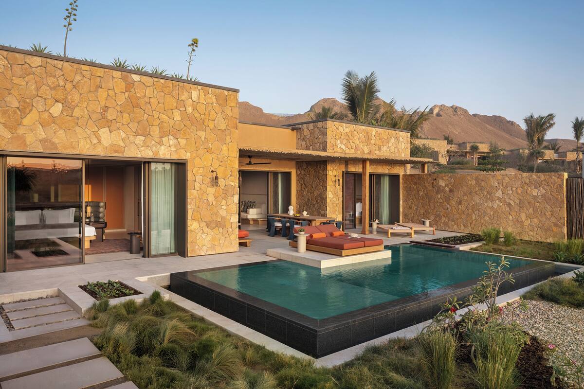Um resort moderno com piscina, área de estar externa e fachada de pedra.