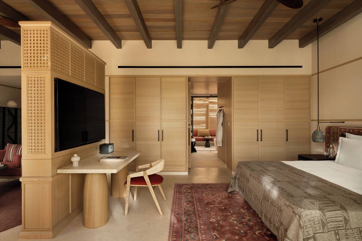Quarto com cama, escrivaninha com cadeira, televisão e armários de madeira.