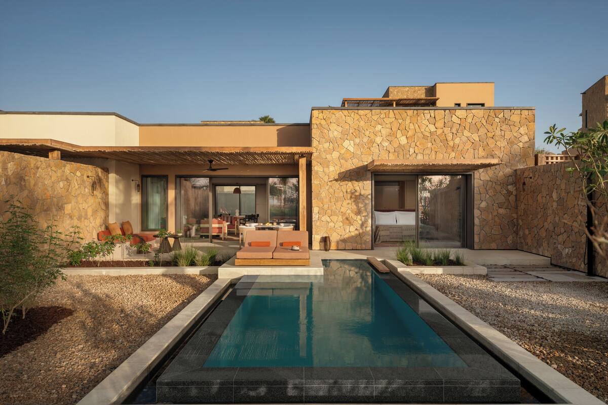 Uma casa moderna com piscina, paredes de pedra e área de varanda.