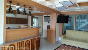 Uma sala de estar moderna com um balcão de atendimento de madeira, um sofá e uma TV fixada na parede.