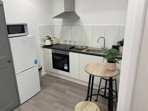 Uma cozinha compacta com micro-ondas, torradeira, pia e um pequeno espaço de refeições com banquetas.