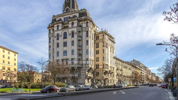 Um edifício grande e histórico, com vários andares e uma torre imponente.
